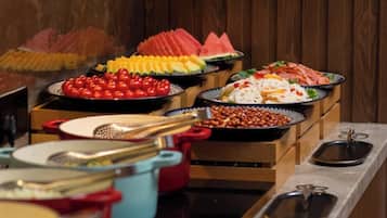 Buffet com diversos pratos, incluindo frutas fatiadas, legumes e carnes.