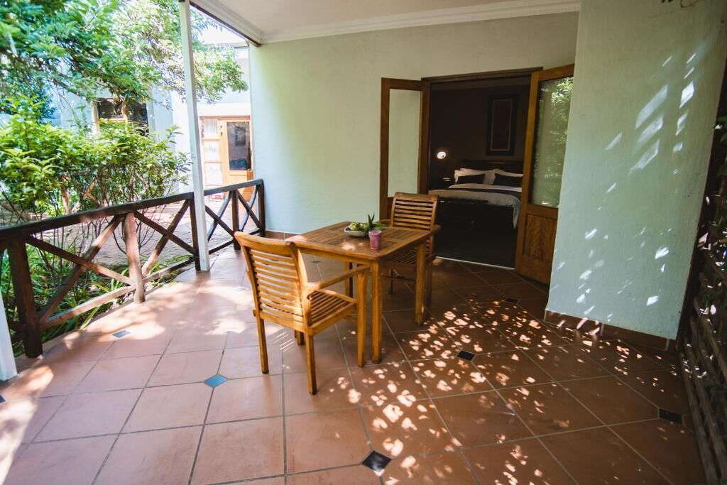 Varanda com mesa e cadeiras de madeira, uma pequena planta e vista para o exterior.