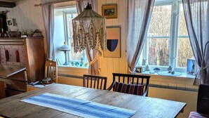 Uma sala de jantar acolhedora com mesa de madeira, cadeiras e luminária pendente.