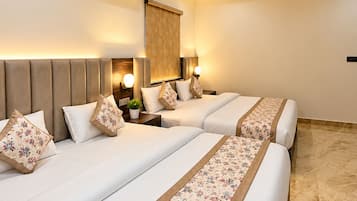 Quarto de hotel com duas camas, um ventilador de teto, aparelho de ar condicionado e cabeceira decorativa.