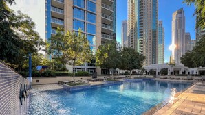 Uma piscina com bordas azulejadas, cercada por espreguiçadeiras e um deck revestido de azulejos.