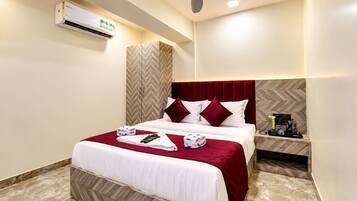 Quarto de hotel com cama, mesa de cabeceira, aparelho de ar condicionado e parede com padrão losango.