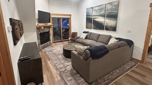 Uma sala de estar com lareira, sofá, mesa de centro e televisão.