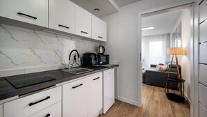 Cozinha moderna com armários brancos, bancada preta e cafeteira.