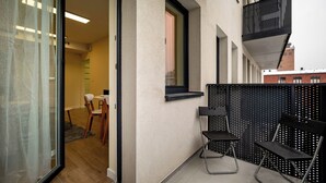 Uma varanda estreita com uma porta de correr de vidro que dá para um quarto com área de jantar.