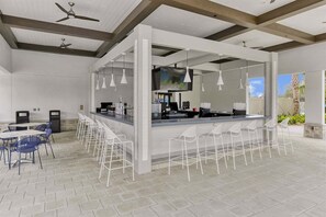 Uma área de bar com banquetas brancas, balcão e ventiladores de teto.