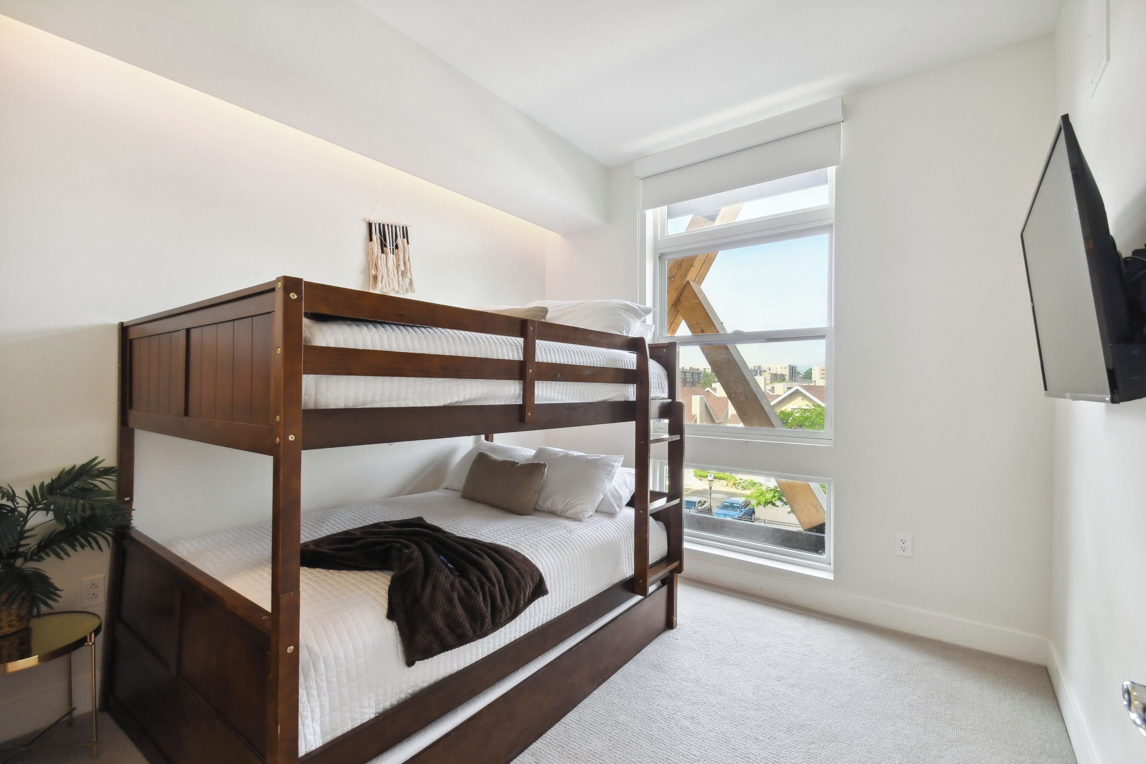 Uma cama de solteiro com vista para a cidade através de uma grande janela.