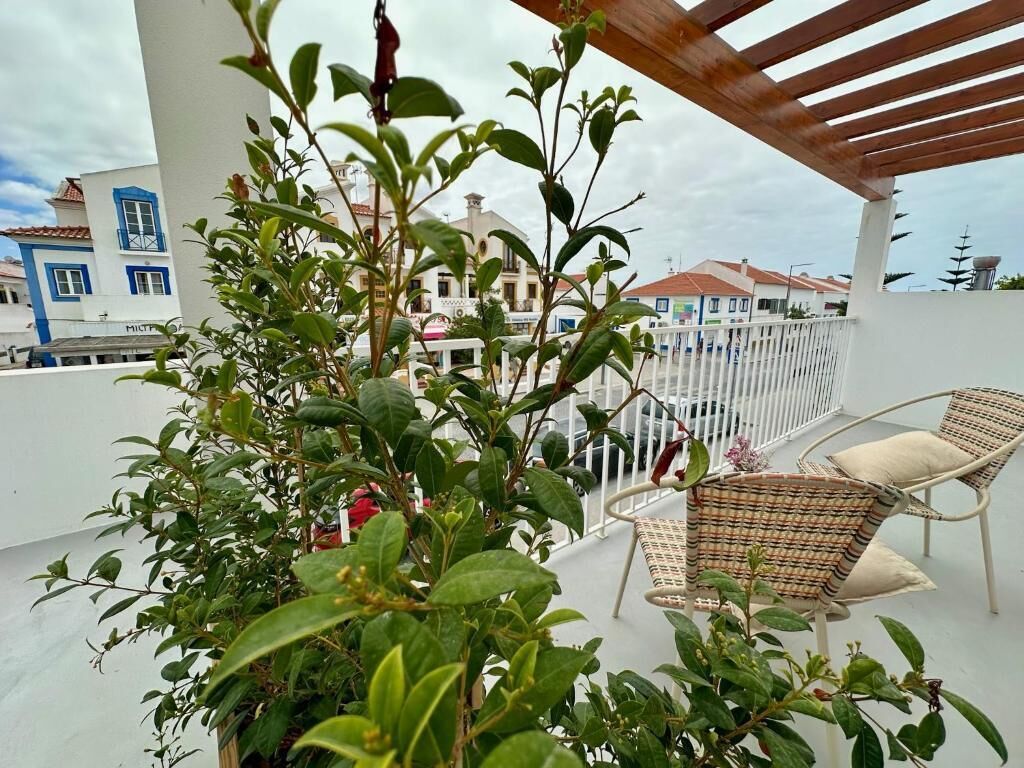 Varanda com cadeiras de vime e plantas em vasos.