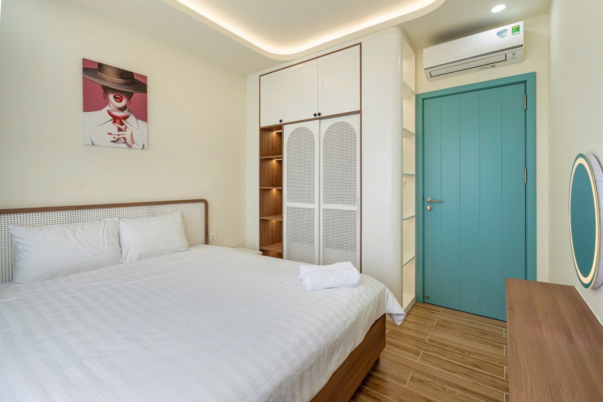 Quarto com cama, guarda-roupa, porta verde-água e aparelho de ar condicionado.