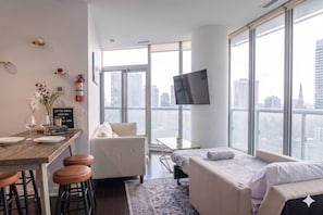 Um apartamento moderno com sala de jantar, sofá, cama e televisão.