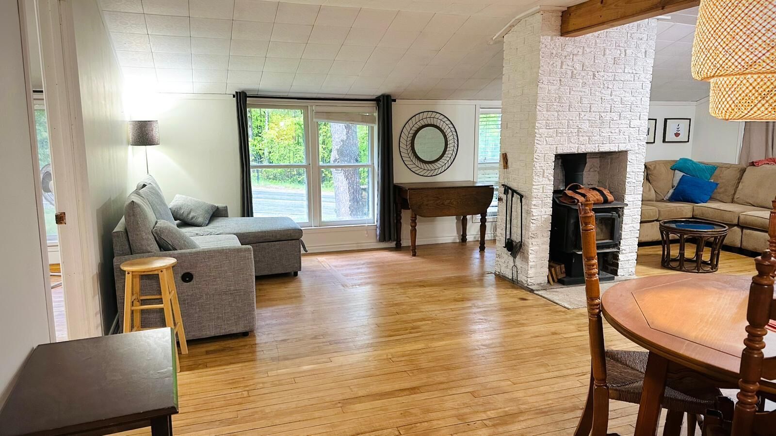Uma sala de estar com lareira, sofá, mesa de jantar e piso de madeira.