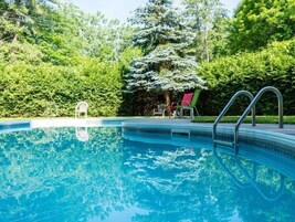 Piscina com escada de metal e uma cadeira vermelha.