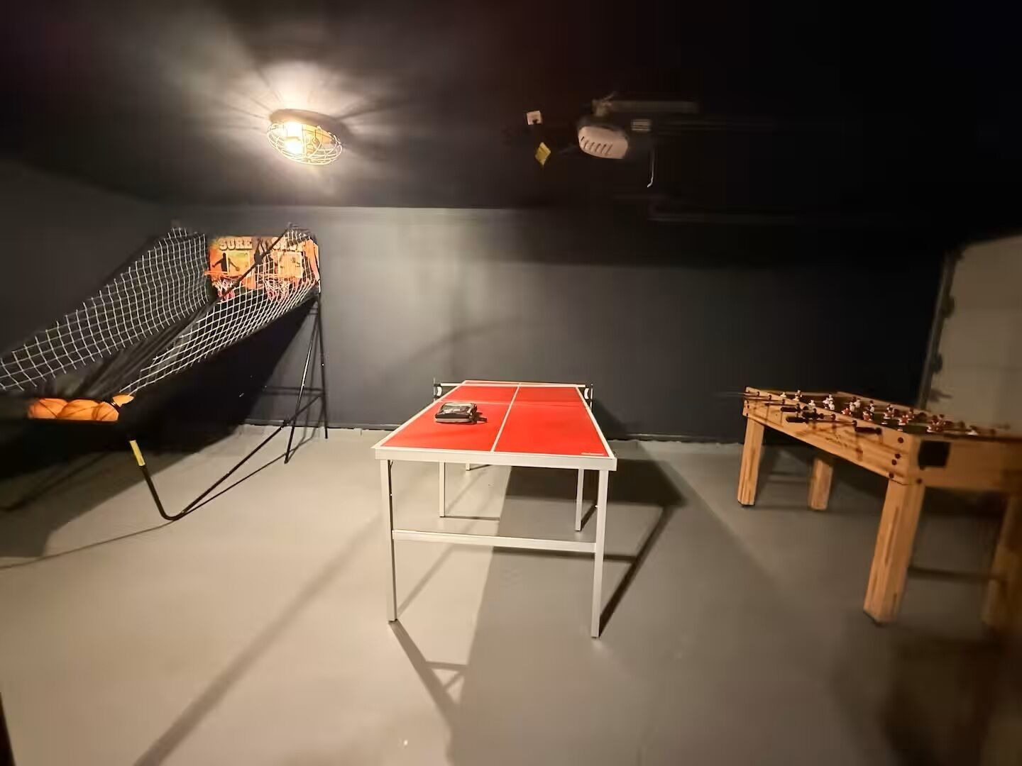 Um quarto com mesa de pingue-pongue, mesa de futebol de mesa e uma rede.