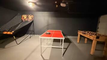 Um quarto com mesa de pingue-pongue, mesa de futebol de mesa e uma rede.