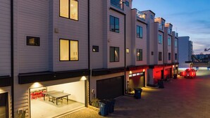 Um edifício residencial de vários andares com área de estar coberta ao ar livre e garagem.