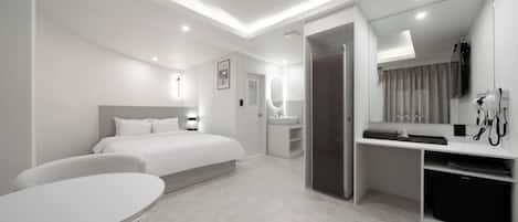 Quarto de hotel moderno com cama, mesa de cabeceira e área de trabalho com espelho.
