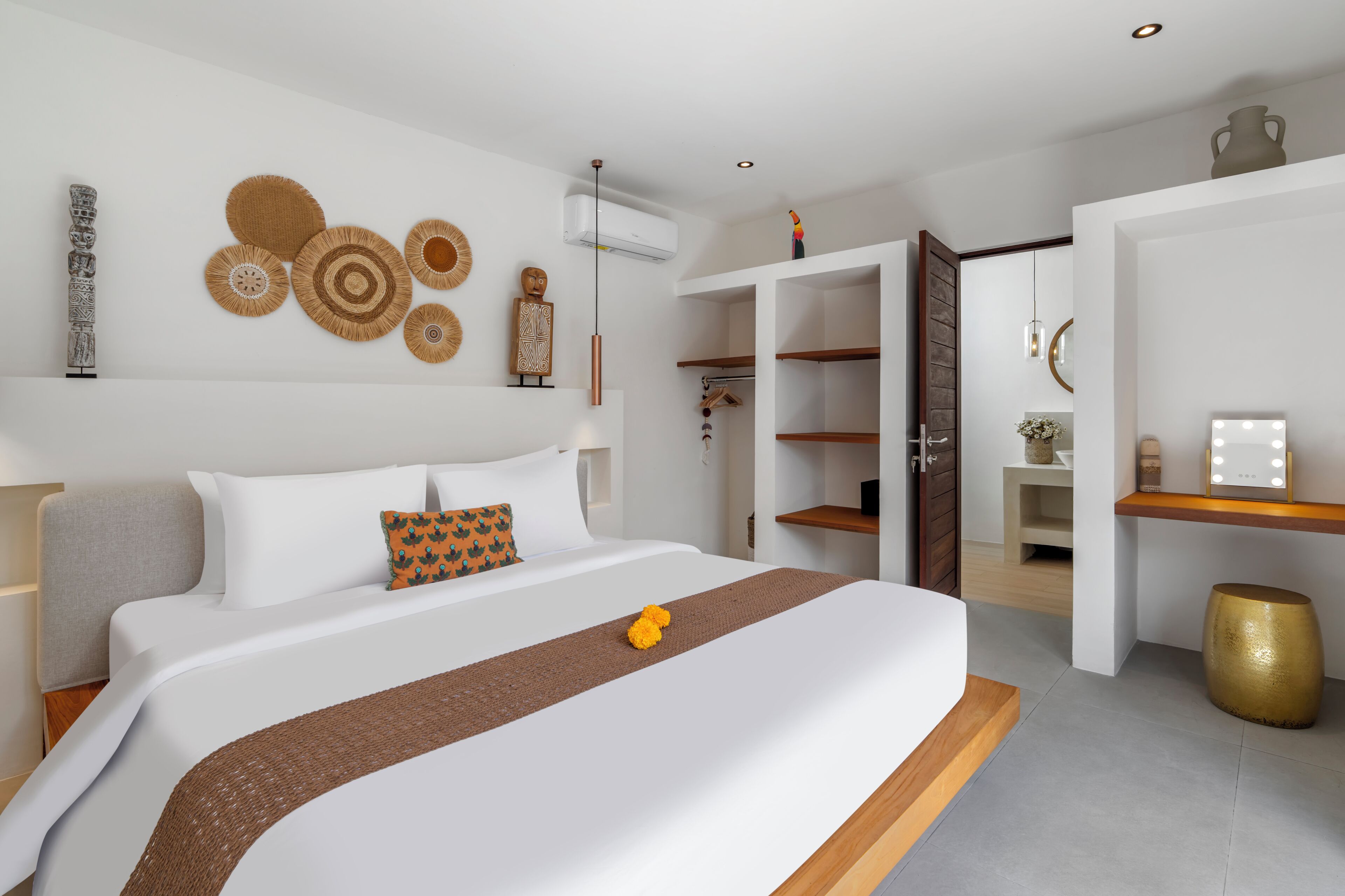 Quarto de hotel moderno com uma cama grande, um guarda-roupa, uma toucador com espelho e um pequeno espaço de estar.