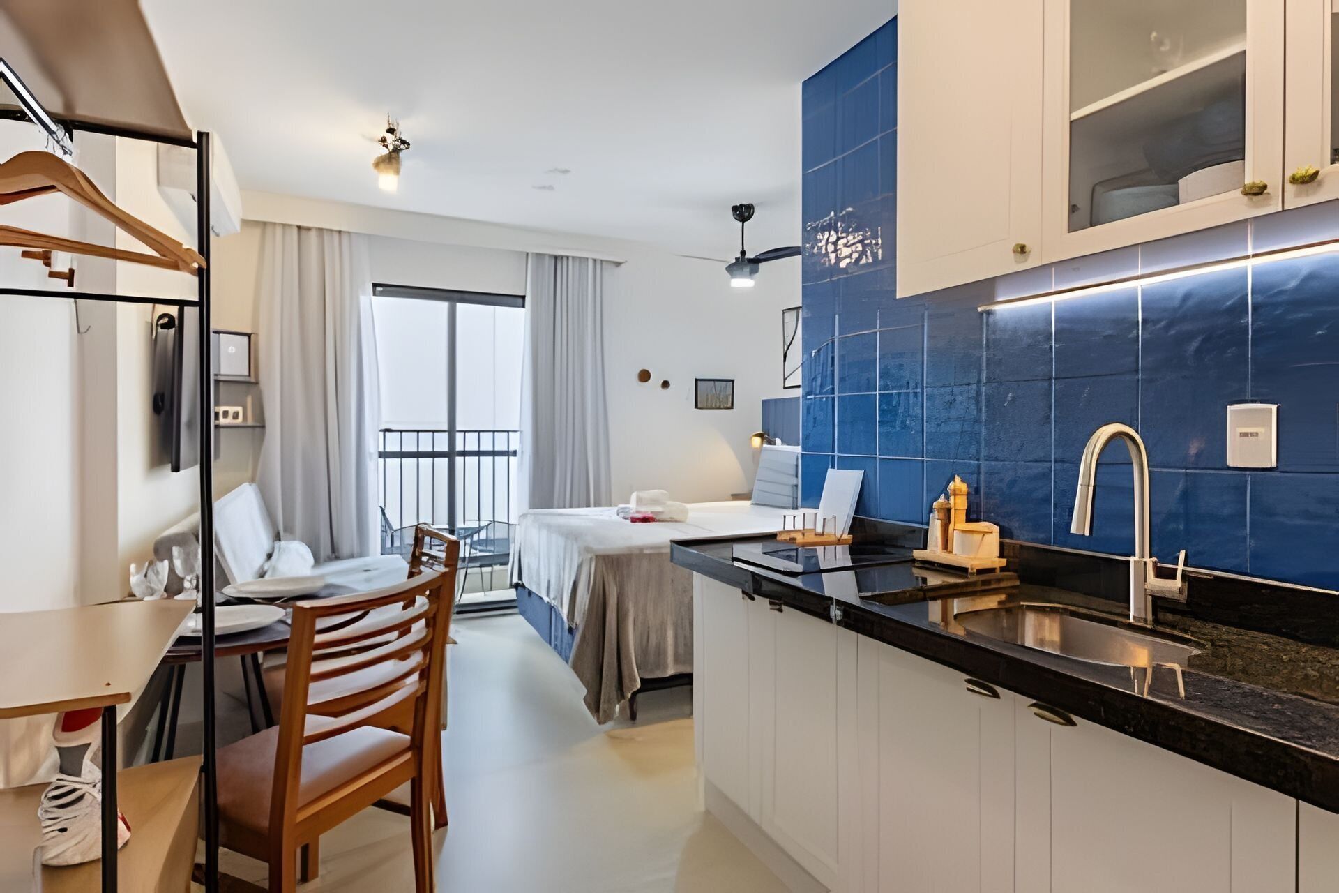 Quarto de hotel moderno com cozinha compacta, área de jantar e varanda.