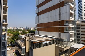 Um edifício com várias andares, varandas, janelas amplas e vista para a paisagem urbana.