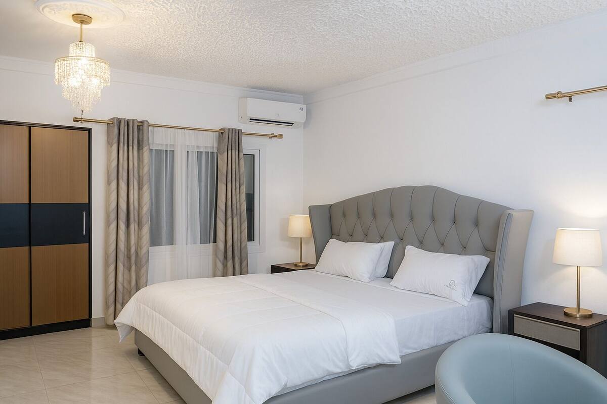 Quarto de hotel com cama, mesas de cabeceira, um candelabro, ar condicionado e um guarda-roupa.