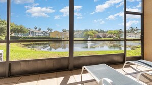 Quarto com grandes janelas dando vista para um lago e edifícios residenciais.