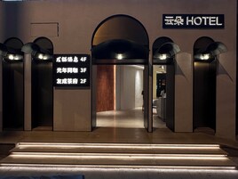 Entrada de hotel com sinalização para a recepção e escadas que levam para dentro.