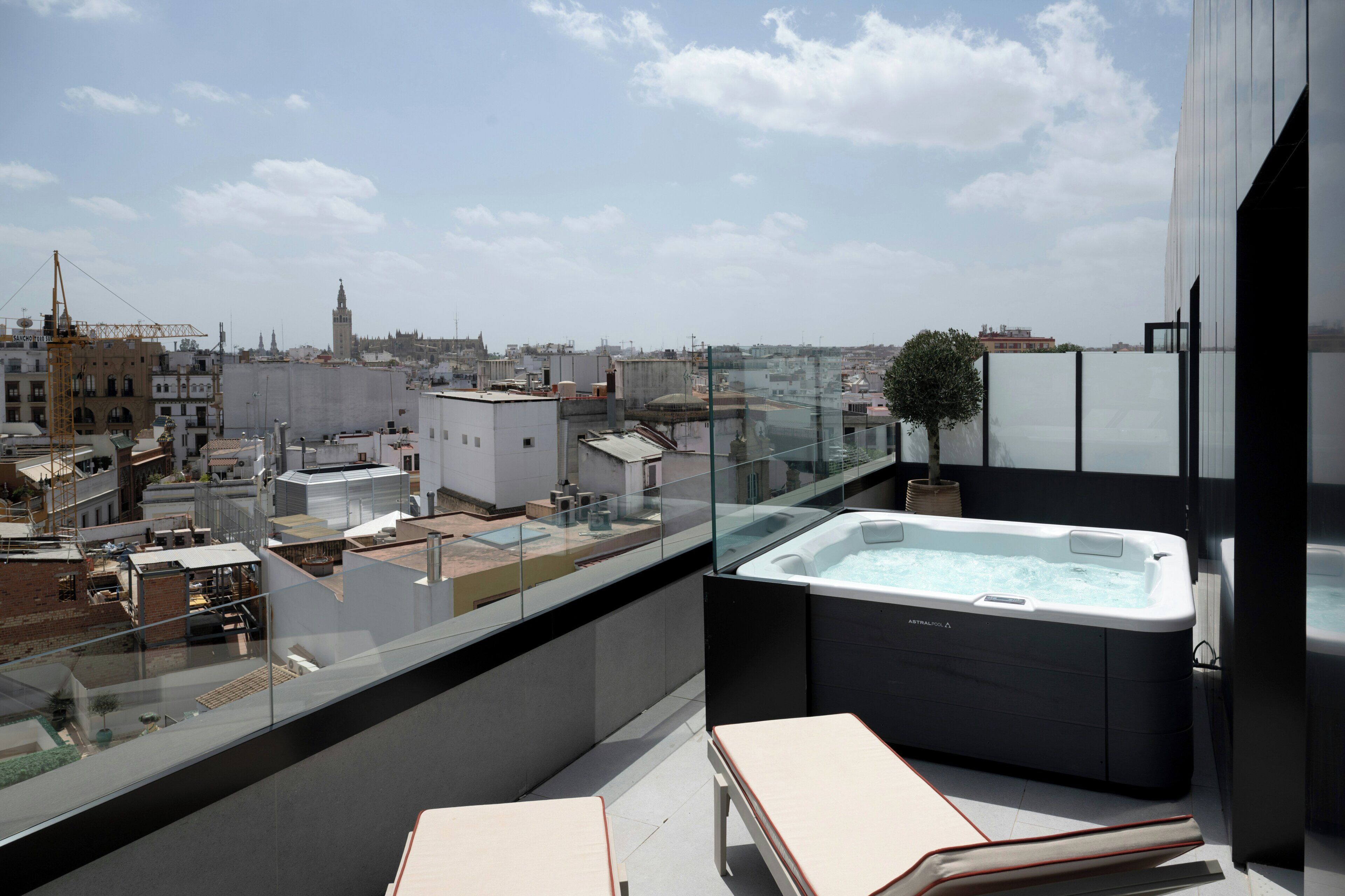 Terraço no telhado com hidromassagem, cadeiras de descanso e vista para a paisagem urbana.