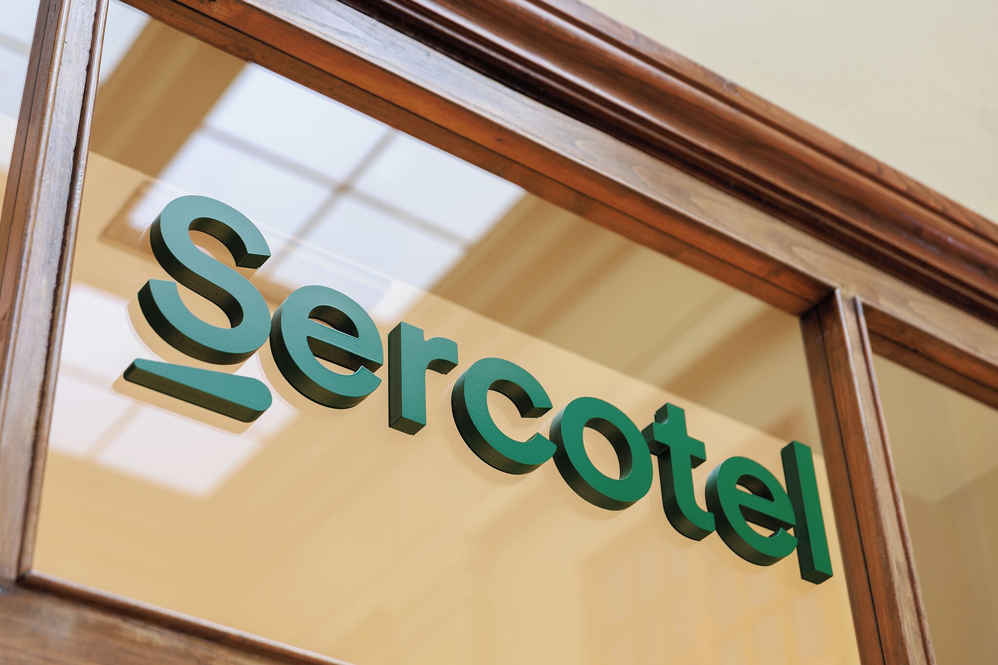 Um letreiro com a palavra 'Sercotel' em letras verdes numa janela.