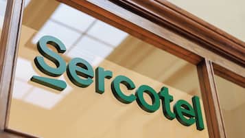 Um letreiro com a palavra 'Sercotel' em letras verdes numa janela.