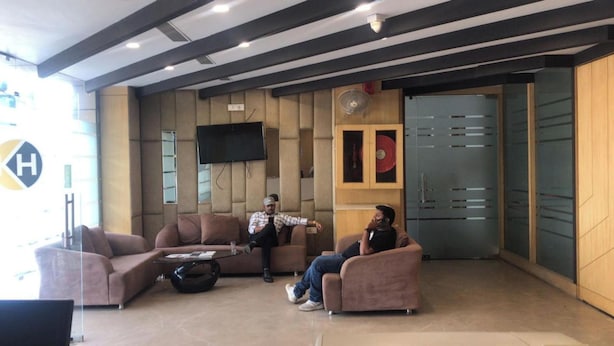 Um saguão com sofás, uma TV de tela plana, um ventilador e armários.