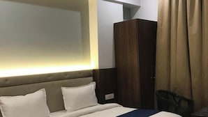 Quarto de hotel com cama, guarda-roupa, ventoinha no teto e janela com cortinas.