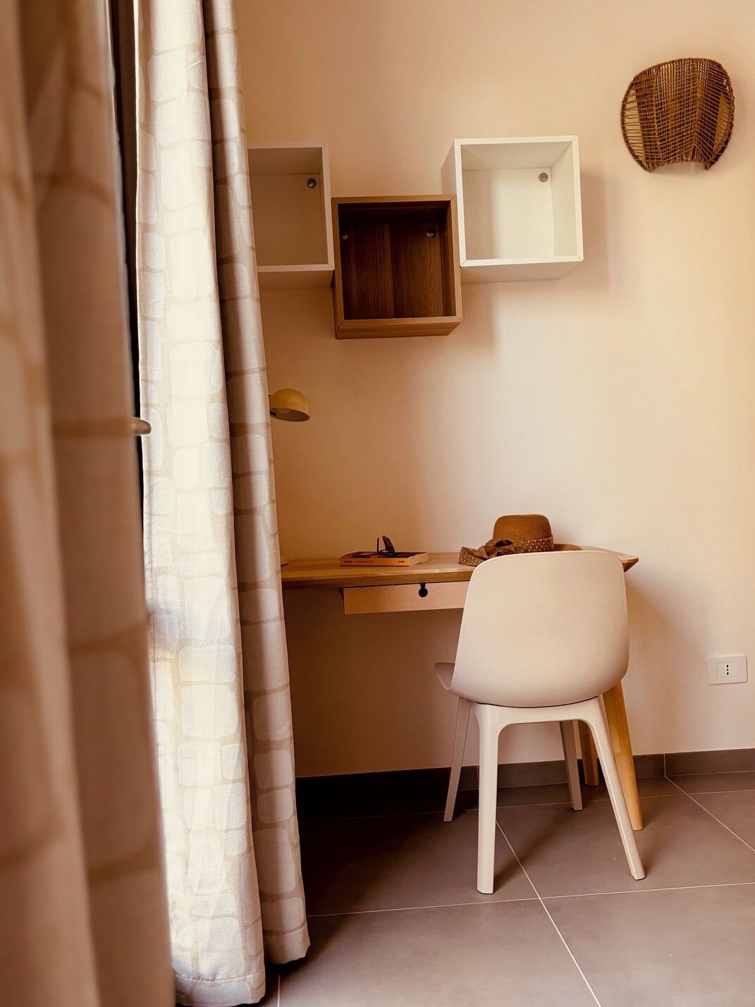 Um espaço de estudo com uma escrivaninha, cadeira e prateleira pequena.