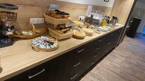 Disposição de buffet com diversos alimentos e uma estação de café.