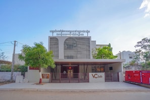 Um edifício moderno com telhado plano, grandes janelas e uma placa com a inscrição 'V Club'.