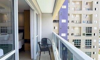 Uma varanda com cama, cadeira e vista de um edifício alto.