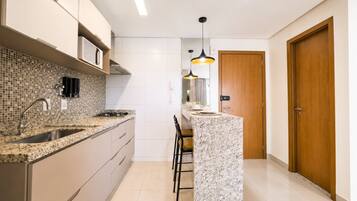 Uma cozinha moderna com bancada de mármore, pia de aço inoxidável e porta de madeira.