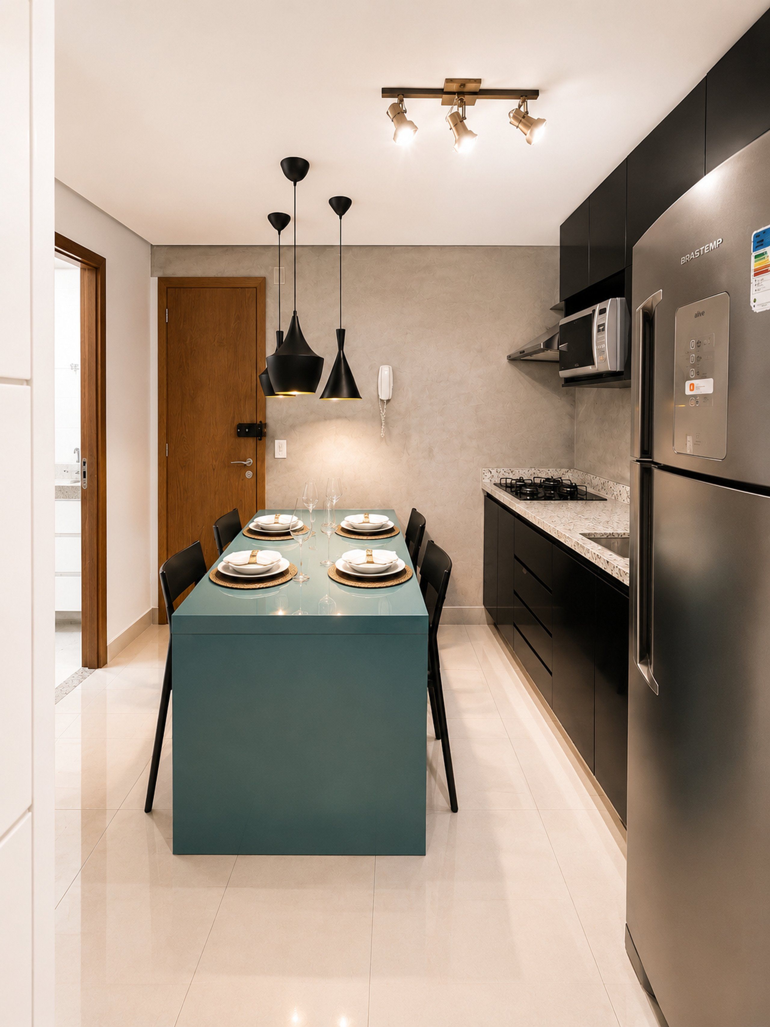 Cozinha moderna com ilha central, armários pretos, eletrodomésticos de aço inoxidável e iluminação pendente.