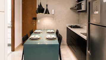 Cozinha moderna com ilha central, armários pretos, eletrodomésticos de aço inoxidável e iluminação pendente.