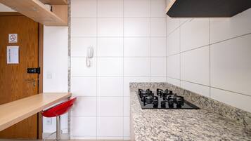 Uma cozinha com bancada de granito, fogão e uma cadeira vermelha.