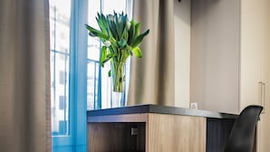 Um espaço de escritório moderno com uma mesa de madeira, uma cadeira preta e uma planta verde em vaso de vidro.