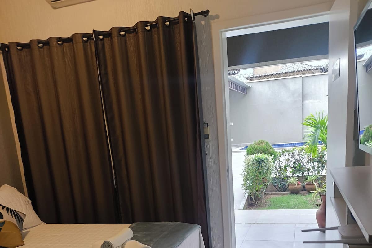 Quarto de hotel com cama, uma pequena escrivaninha e vista para o exterior.
