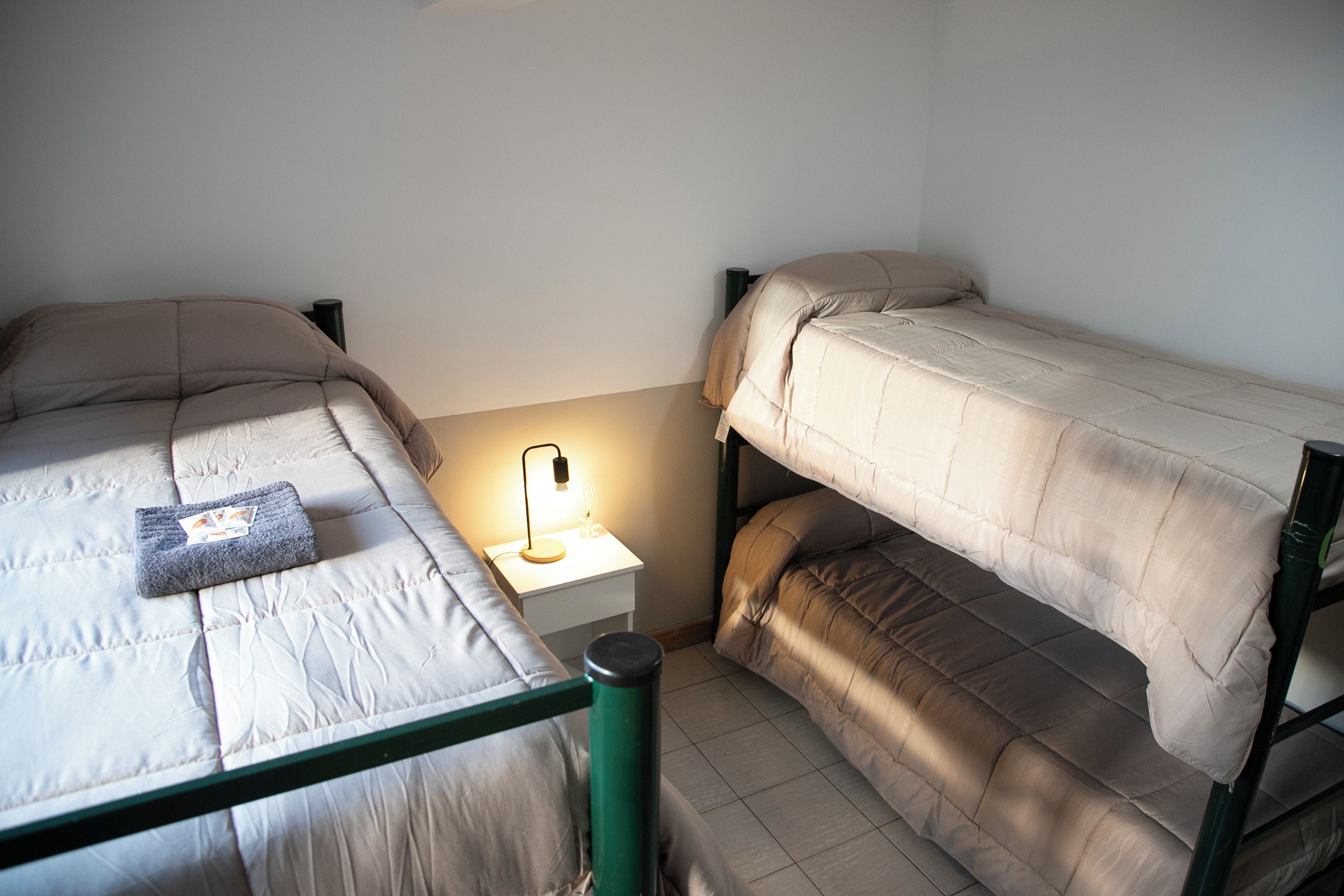 Quarto com beliche, mesa de cabeceira e luminária.
