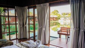 Quarto com cama, um banco e vista para a água.