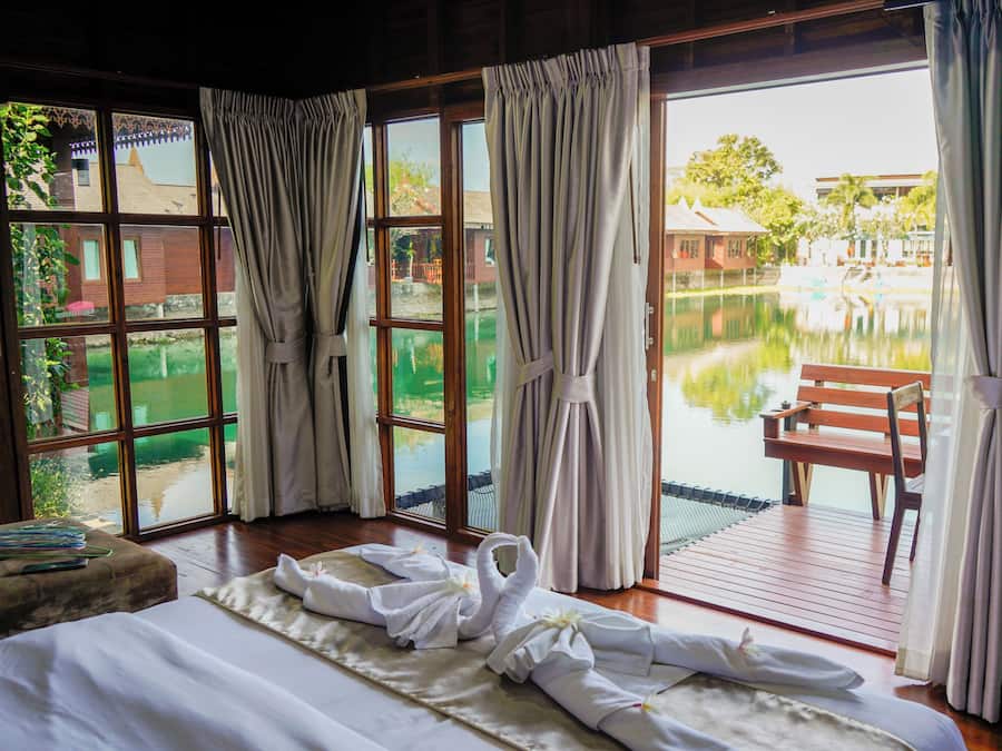 Quarto com cama, um banco e vista para a água.