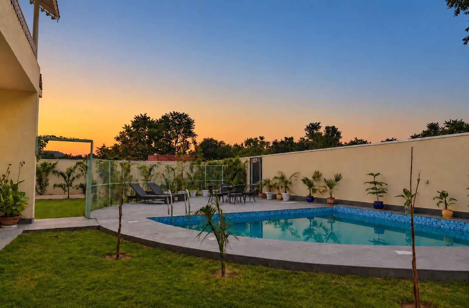 Uma piscina com um deck ao redor, área gramada e uma cerca delimitando o espaço.