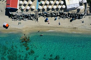 Praia particular, areia branca, espreguiçadeiras, guarda-sóis 