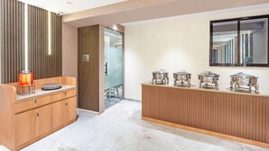 Um lobby de hotel moderno com um balcão de recepção em madeira, uma divisória de vidro e um espelho fixado na parede.