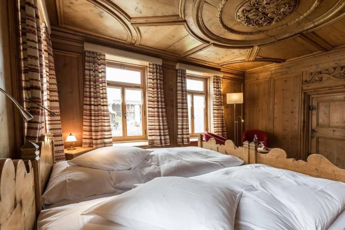 Quarto de madeira tradicional com uma cama grande, cortinas e um candelabro.