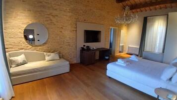 Quarto com parede de tijolos, televisão de tela plana, sofá, cama e lustre.