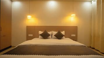 Quarto de hotel com uma cama grande, duas luminárias de cabeceira e uma cortina na janela.